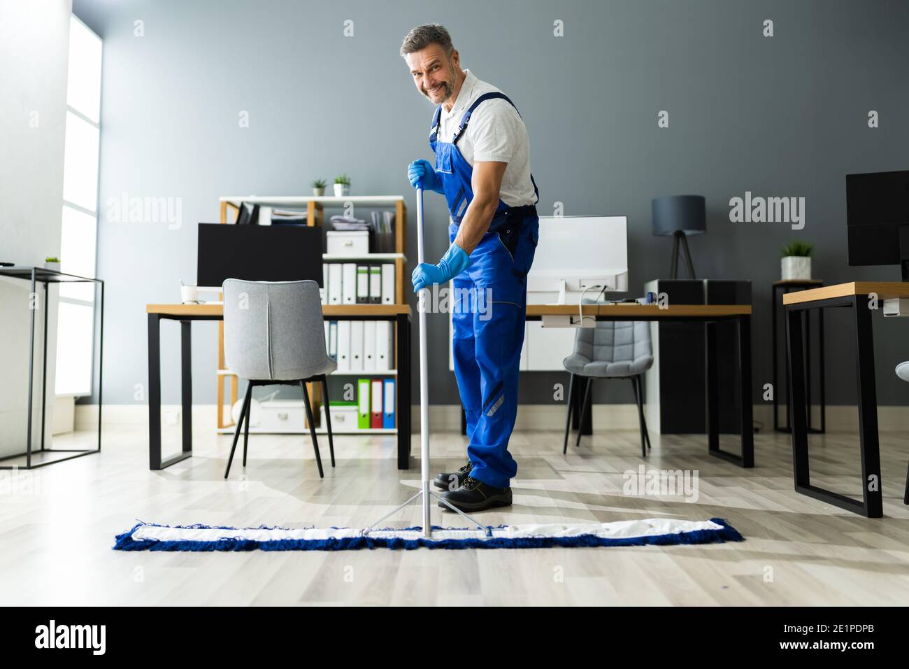 Male Janitor Mopping Floor In Face Mask In Office Stock Photo - Alamy