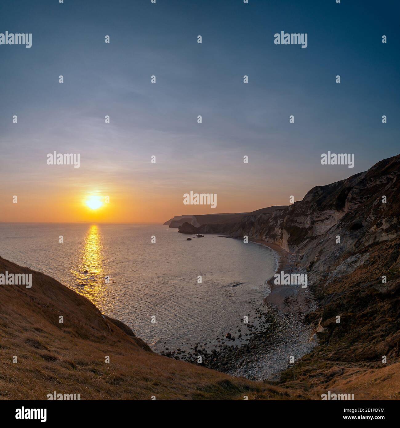 Sunset overlooking a beach in a small bay with cliffs with sun and ...