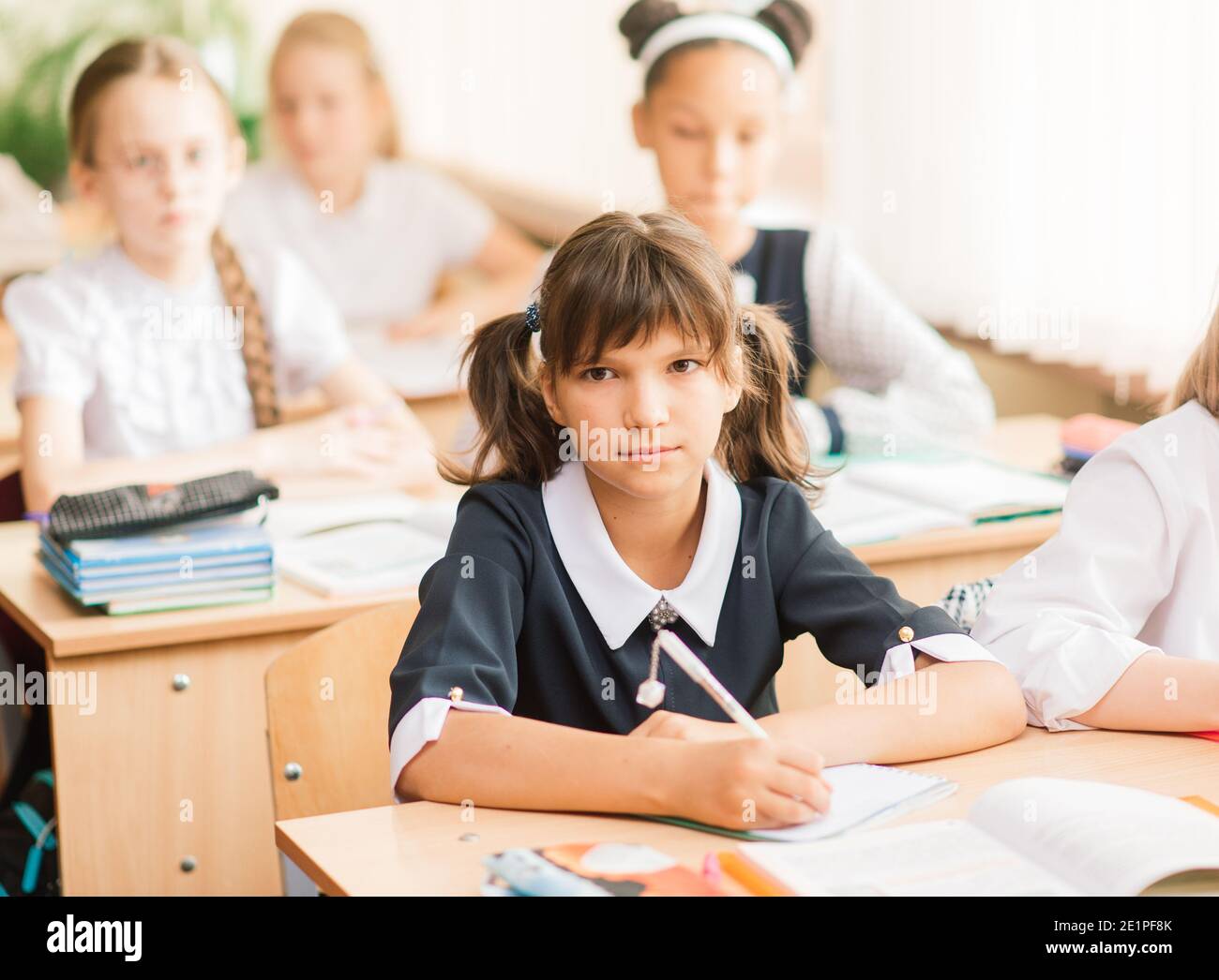 Elementary schoolchildren writing in books in classroom Stock Photo - Alamy