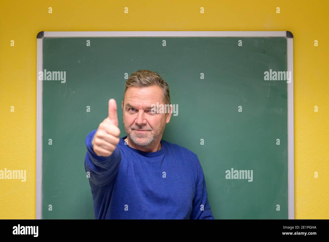 Male teacher giving a thumb up gesture to show a successful answer or ...