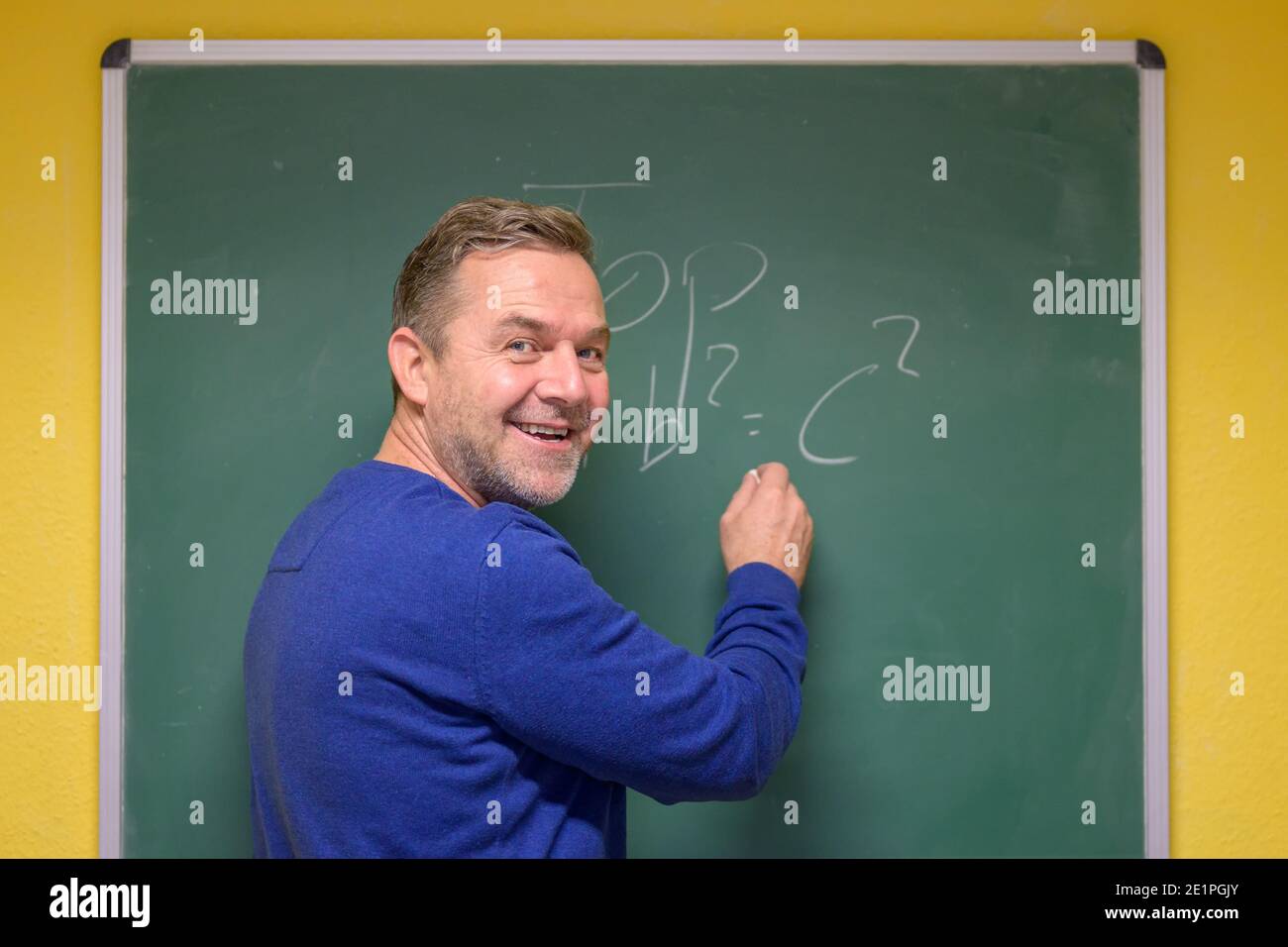 Happy smiling male teacher giving a mathematics class turning to look ...