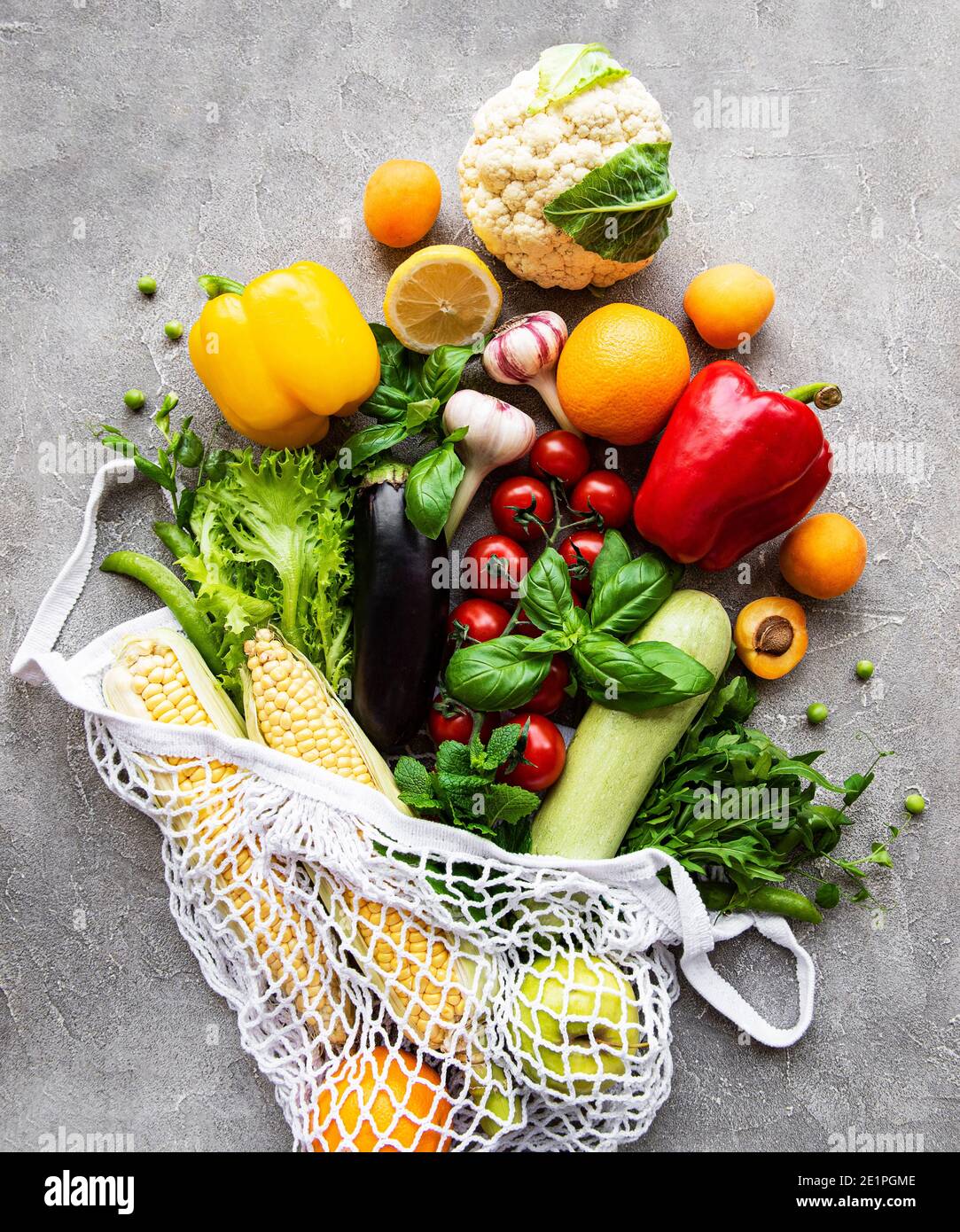 Fresh vegetables and fruits on eco string bag on a concrete background ...