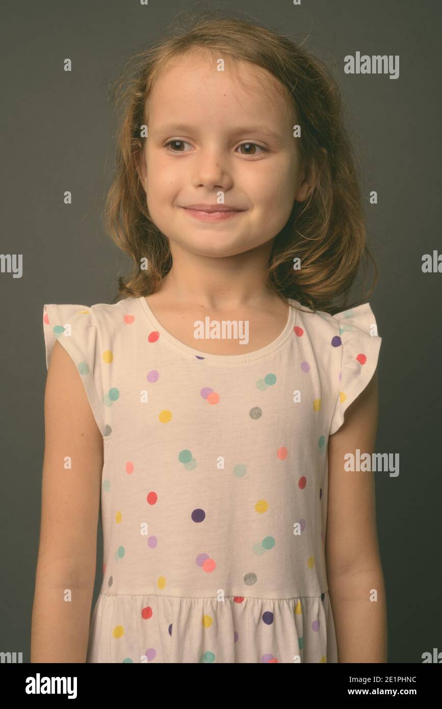 Cute young girl with blond hair against gray background Stock Photo - Alamy