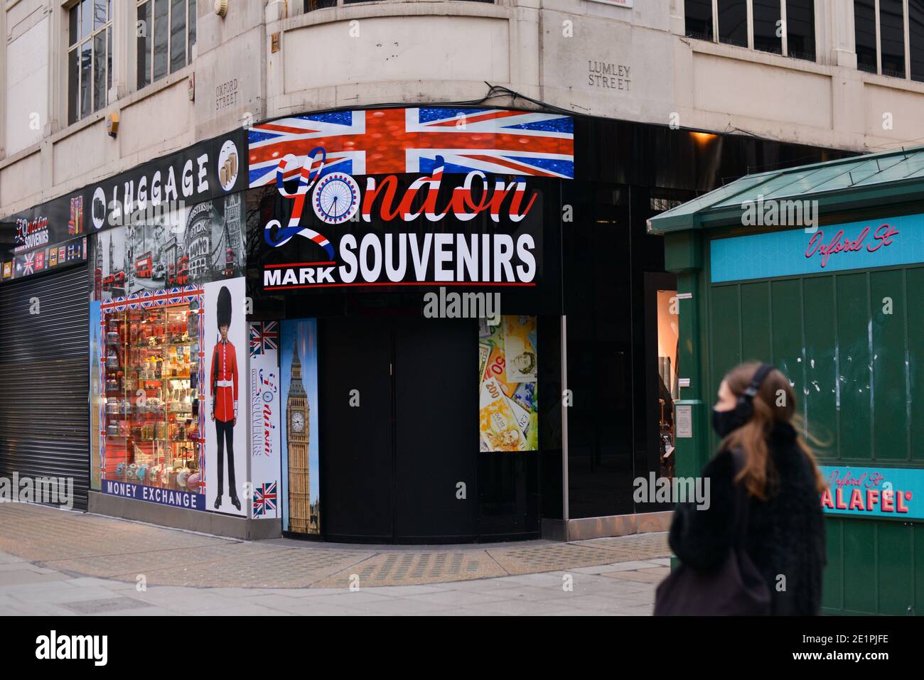 A woman walks past a permanently closed shop, on almost abandoned ...