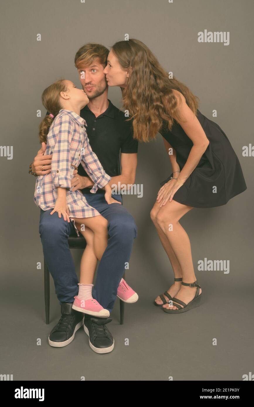 Young happy family bonding together against gray background Stock Photo ...