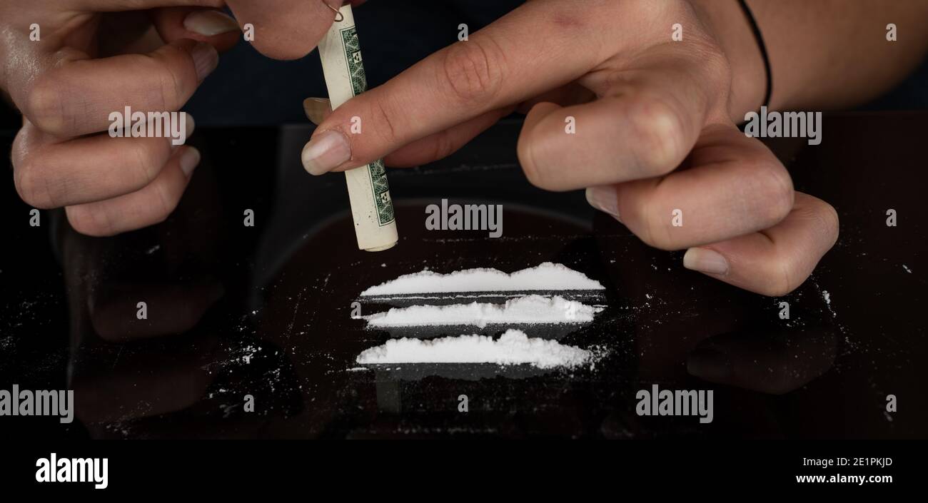 Drug addict woman snorting cocaine powder with rolled dollar banknote ...