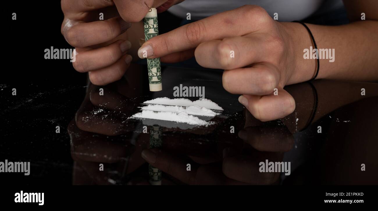 Drug addict woman snorting cocaine powder with rolled dollar banknote ...