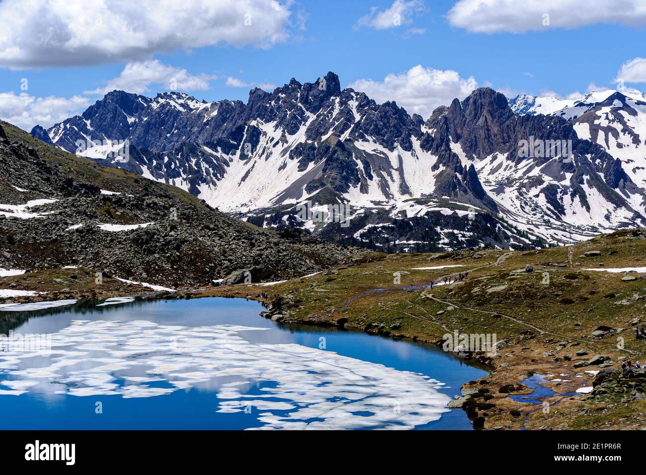 High-altitude lake still covered with ice. In the background a grey ...
