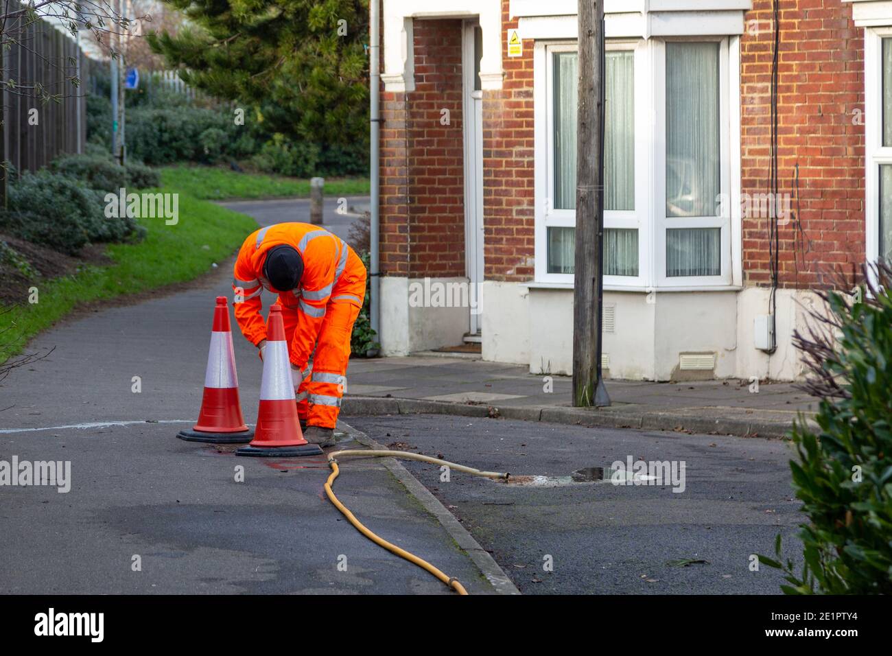 A maintenance worker in high visibility clothing laying out cones in a ...