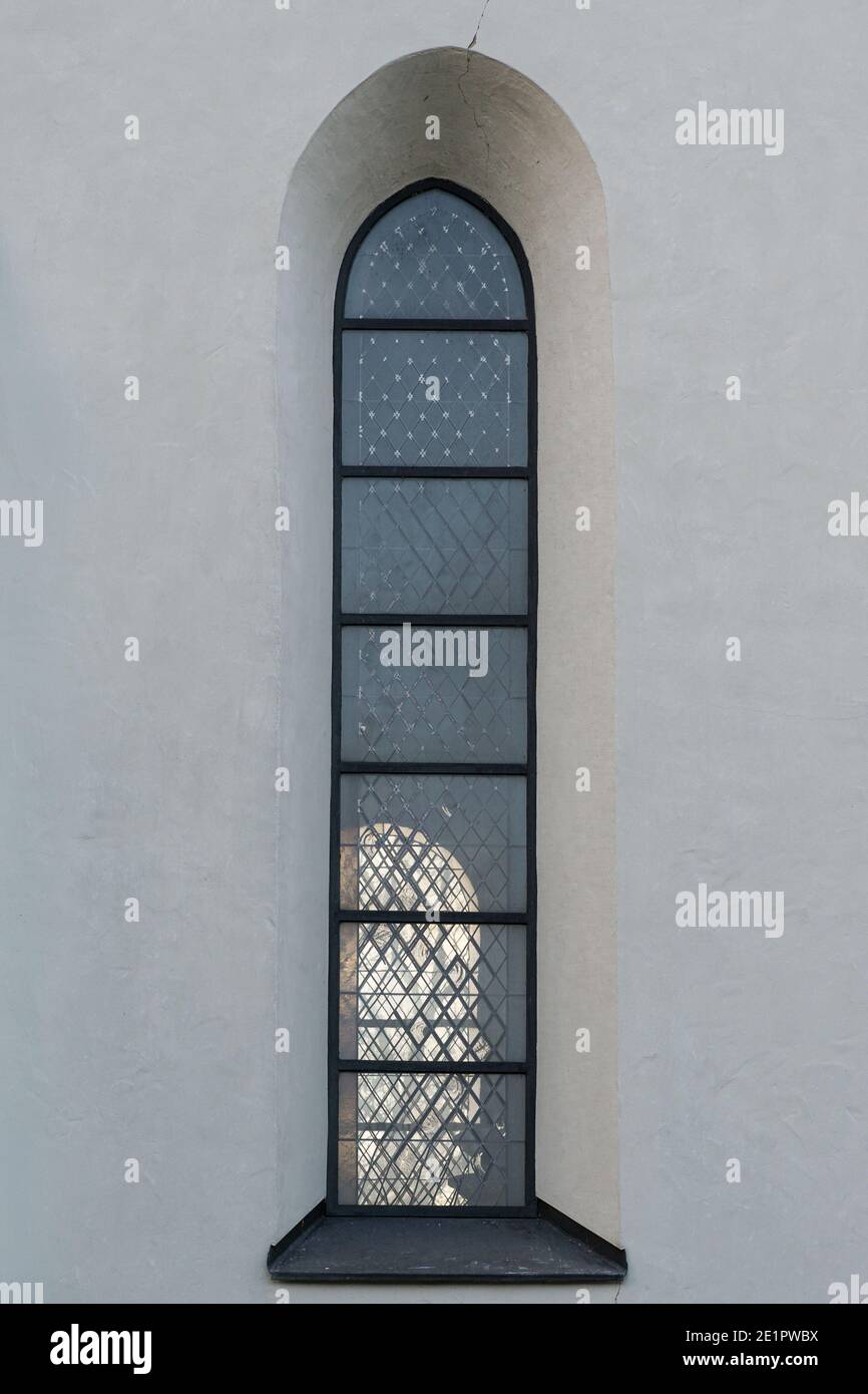A church window in the shade offers a view of another window in the ...
