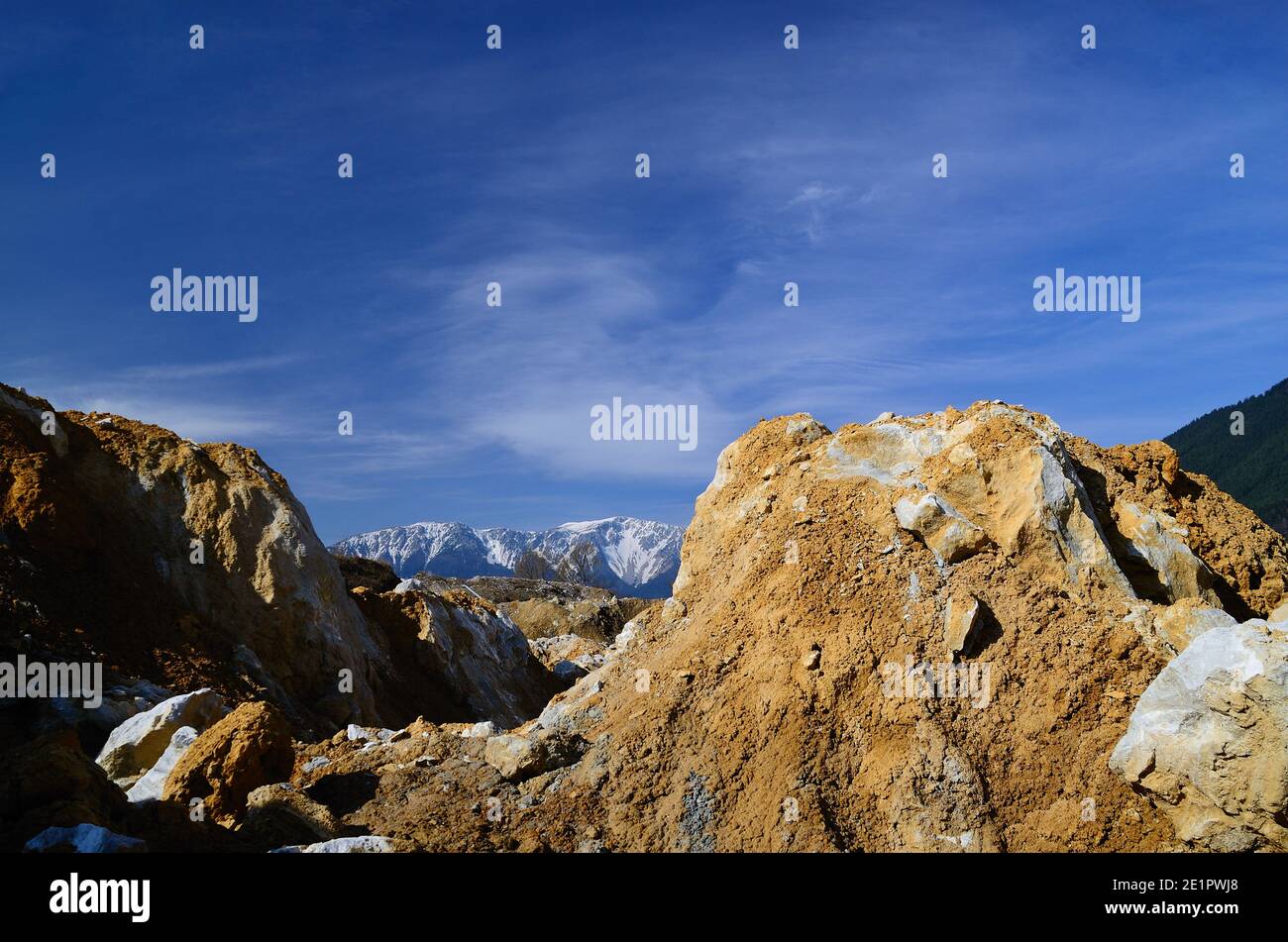 large quarry in the mountains with snow mountain in the background ...