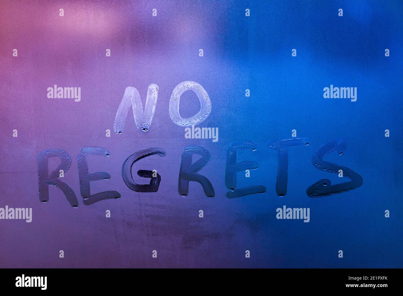 words no regrets hand written on purple-blue night foggy window glass ...