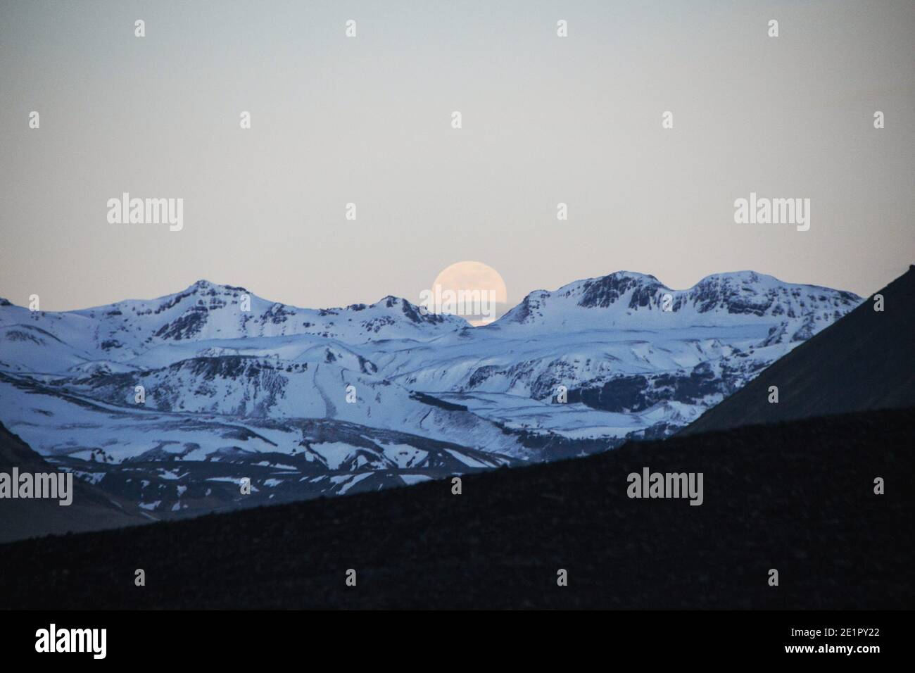 Full moon rising over snow capped ice mountain peaks near ...