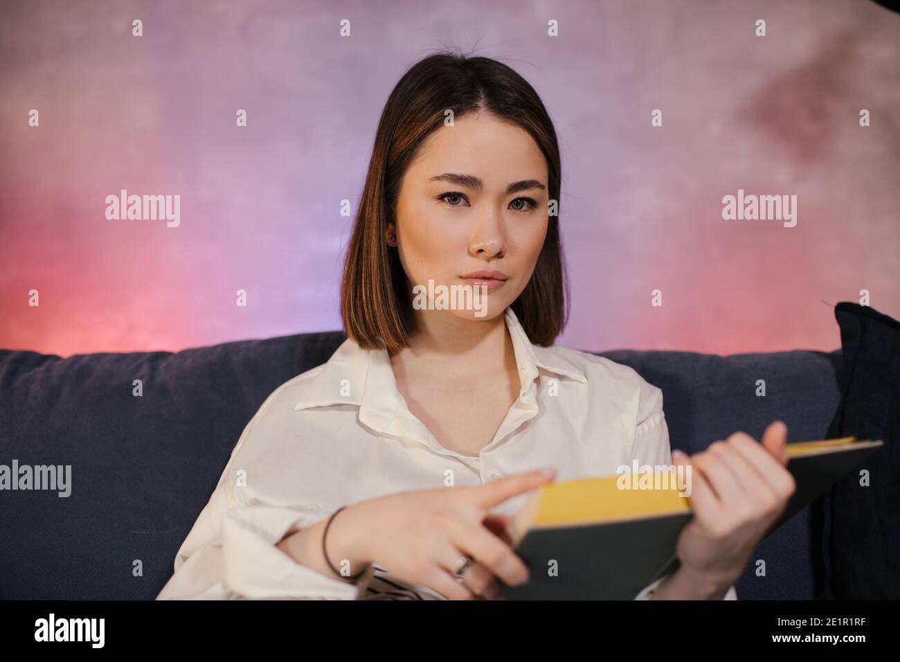 Young Asian girl reading a book. The girl is sitting on the couch. Cozy ...