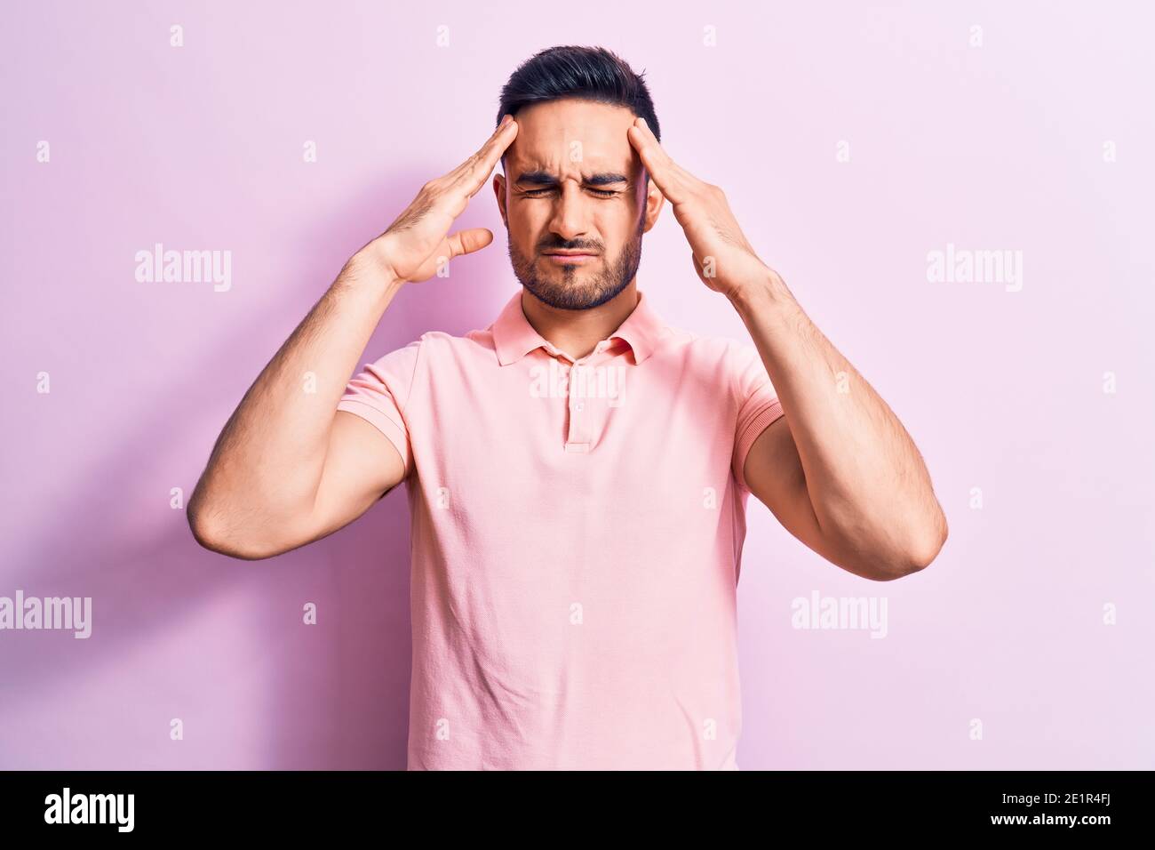 Young handsome man with beard wearing casual polo standing over pink ...