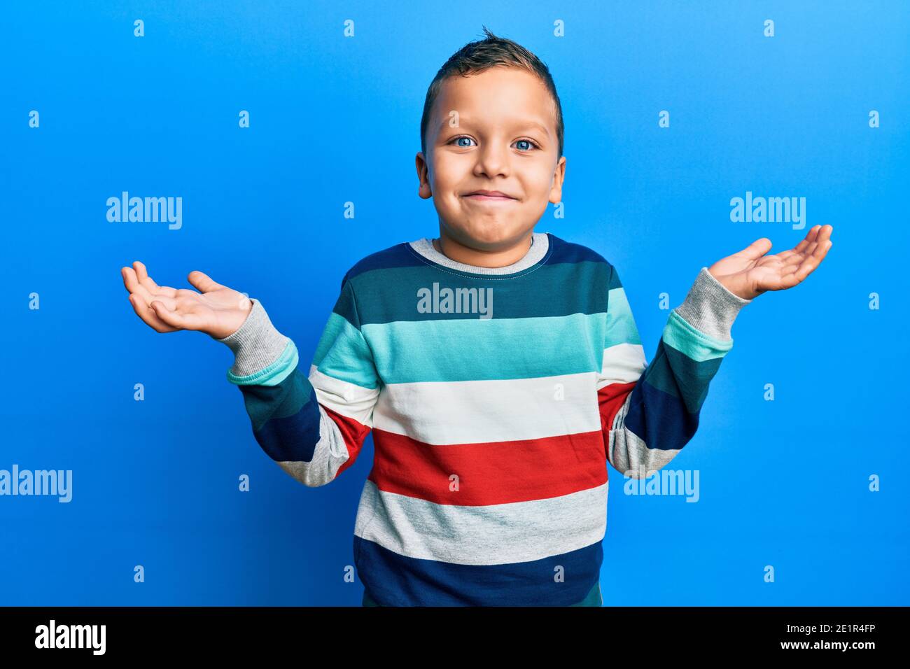 Little kid boy wearing striped sweater clueless and confused with open ...