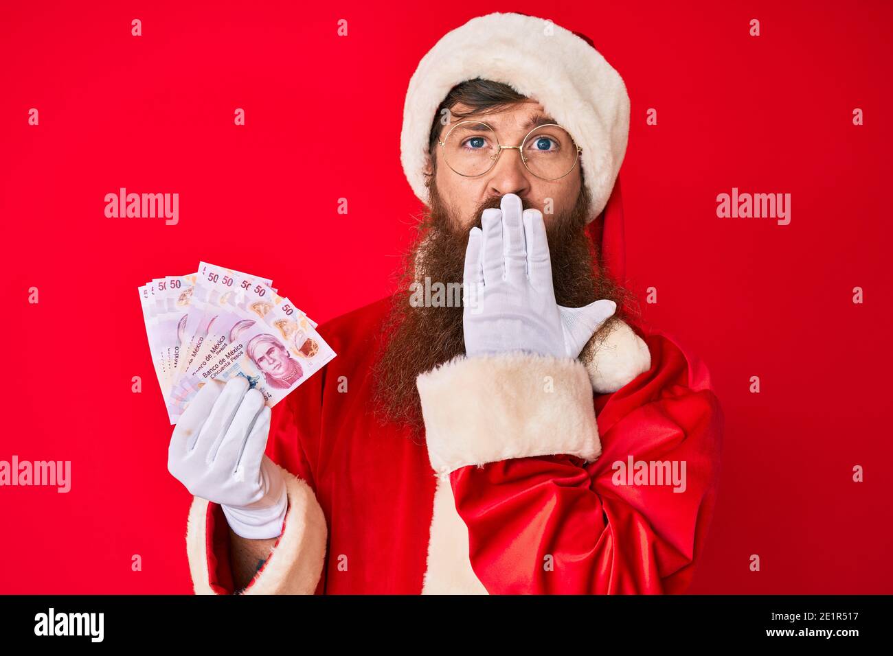 Handsome young red head man with long beard wearing santa claus costume ...