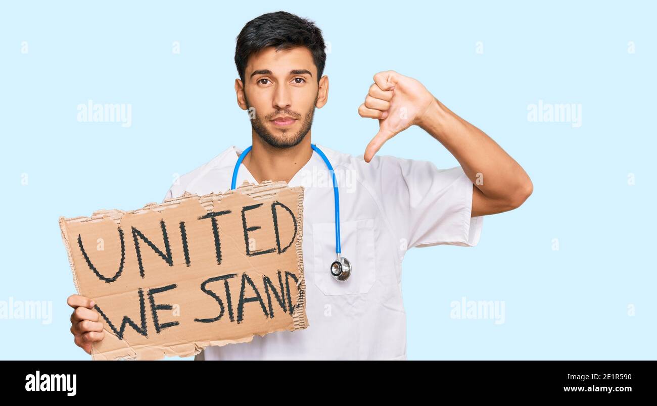 Young handsome man wearing doctor uniform holding united we stand ...