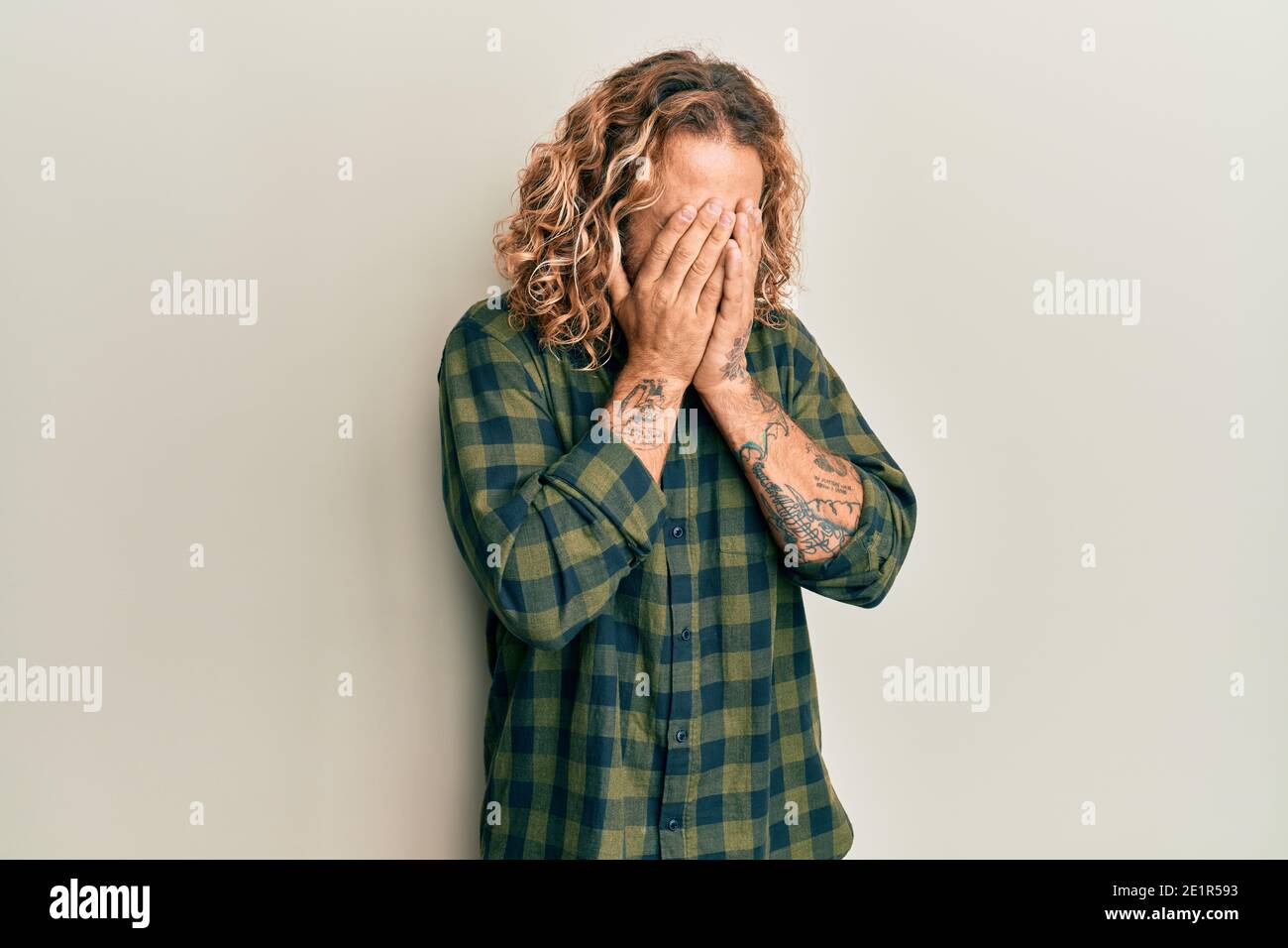 Handsome man with beard and long hair wearing casual clothes with sad ...