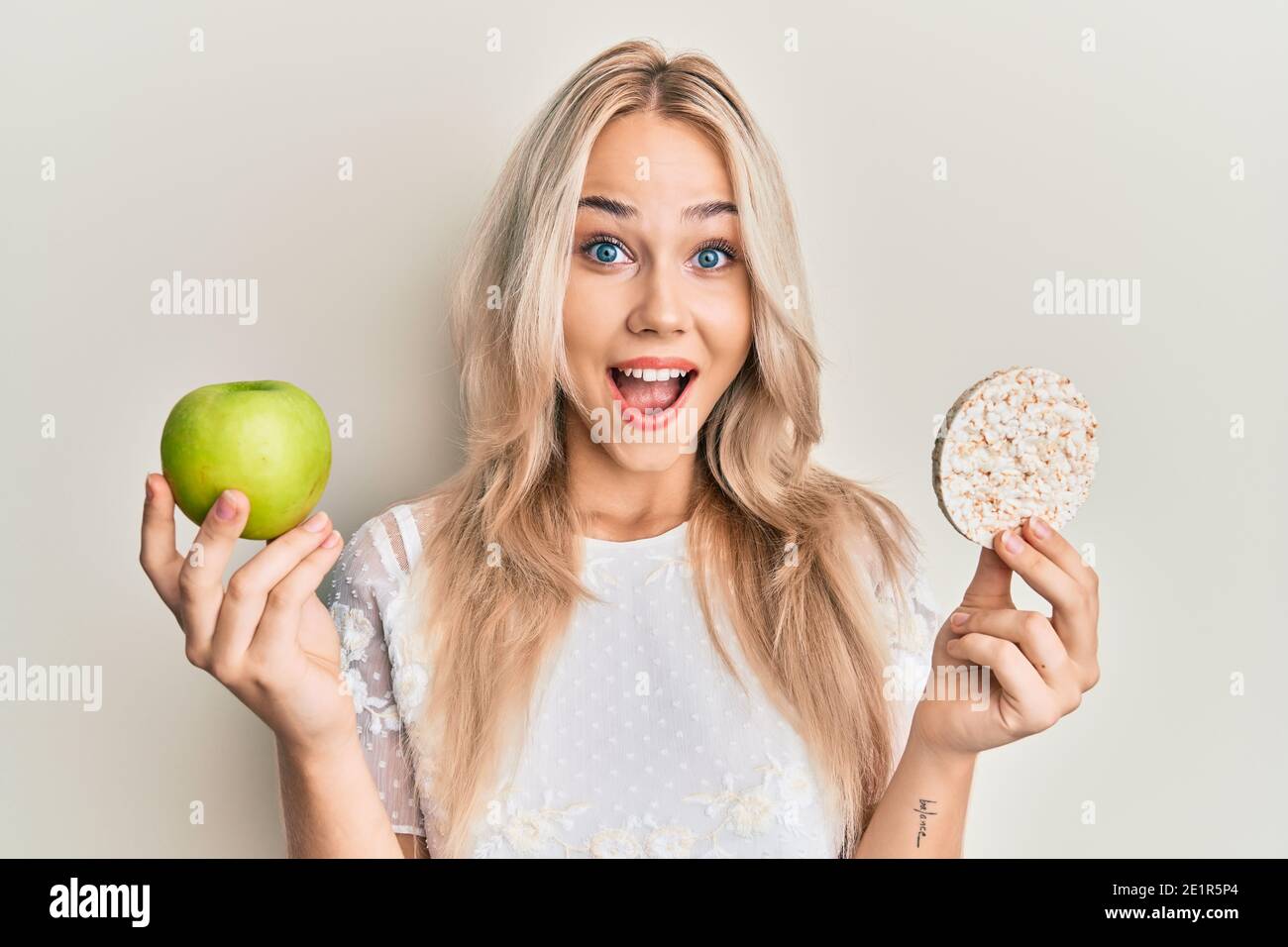 Beautiful caucasian blonde girl holding nachos and healthy green apple ...