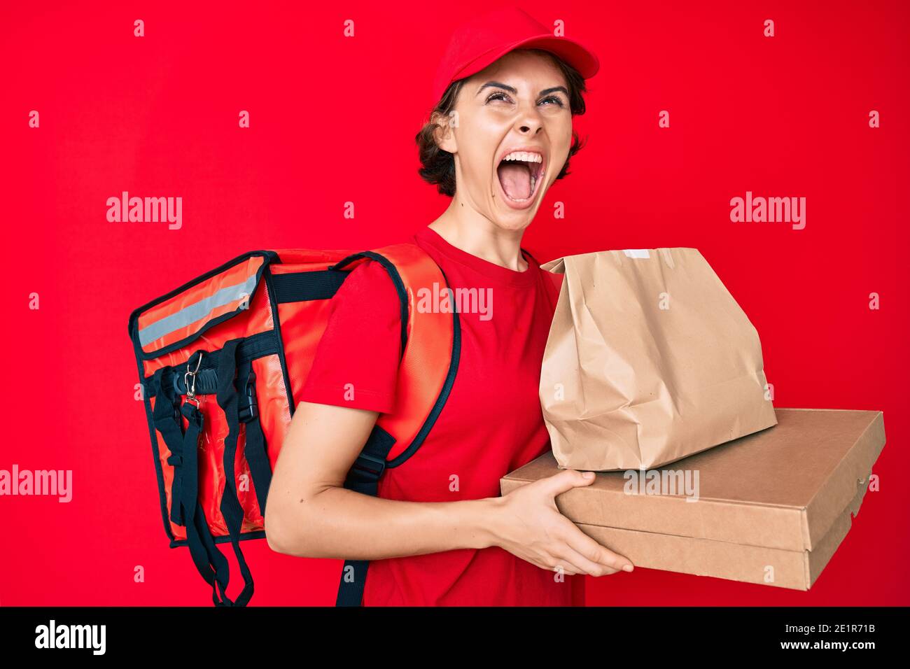 Young hispanic woman holding take away paper bag angry and mad ...