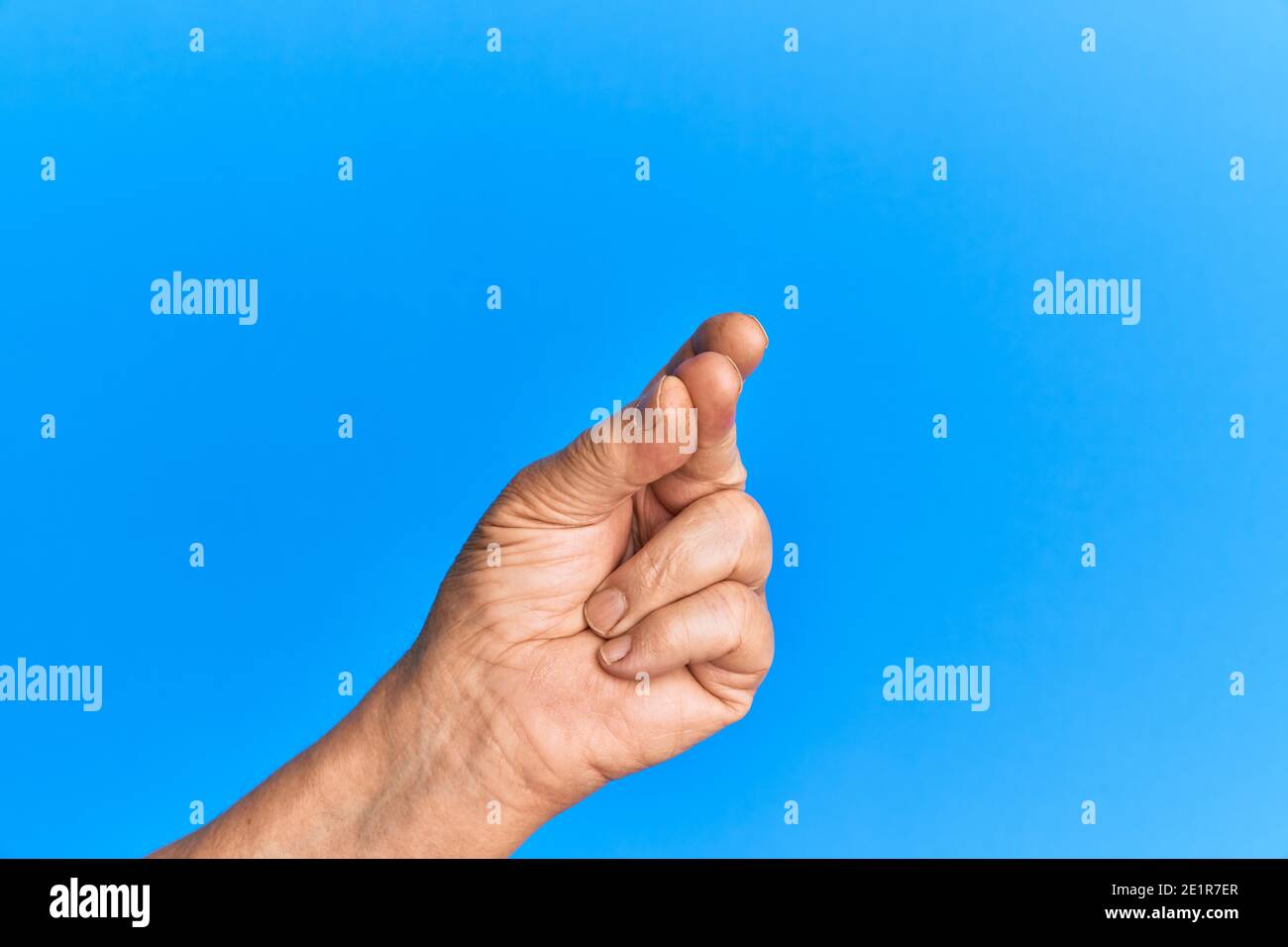 Hand of senior hispanic man over blue isolated background snapping ...