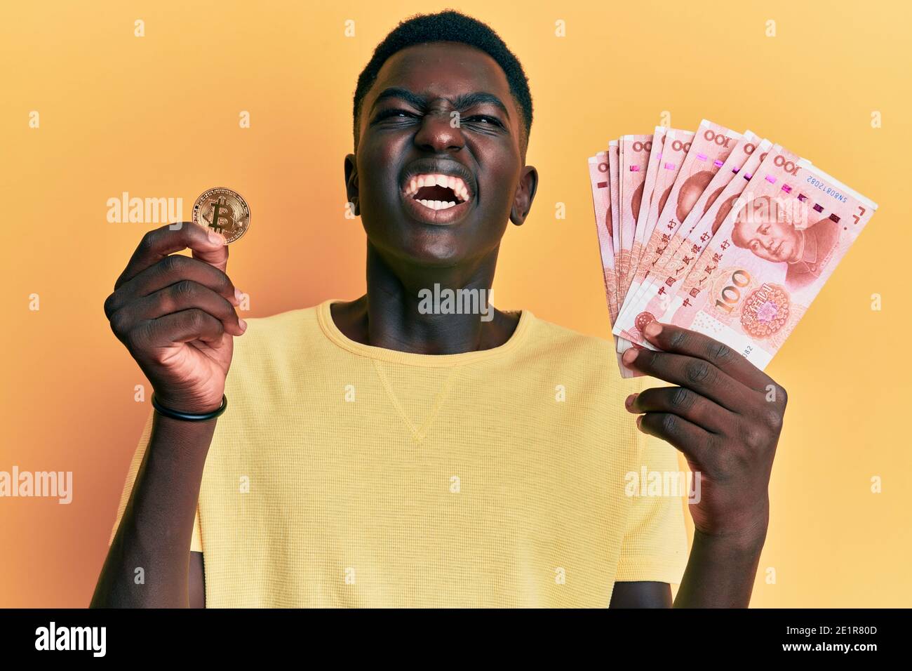 Young african american man holding yuan chinese banknotes and bitcoin ...