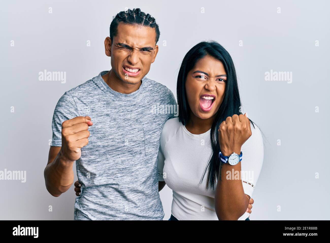 Young latin couple wearing casual clothes angry and mad raising fist ...
