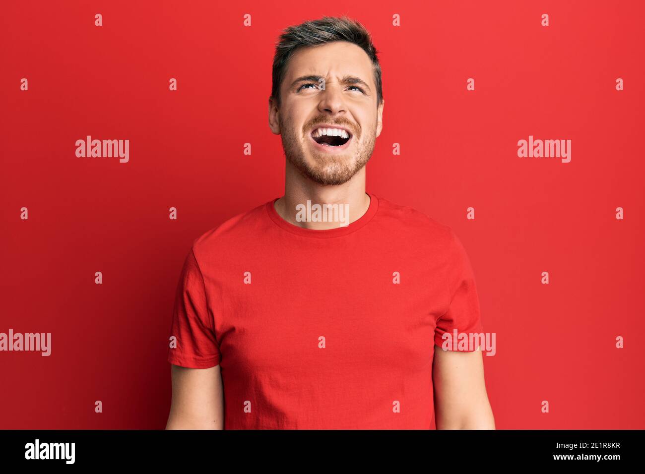 Handsome caucasian man wearing casual red tshirt angry and mad ...