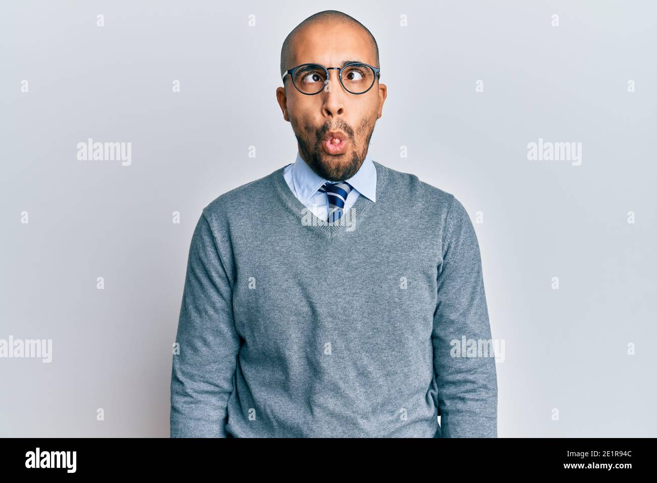 Hispanic adult man wearing glasses and business style making fish face ...