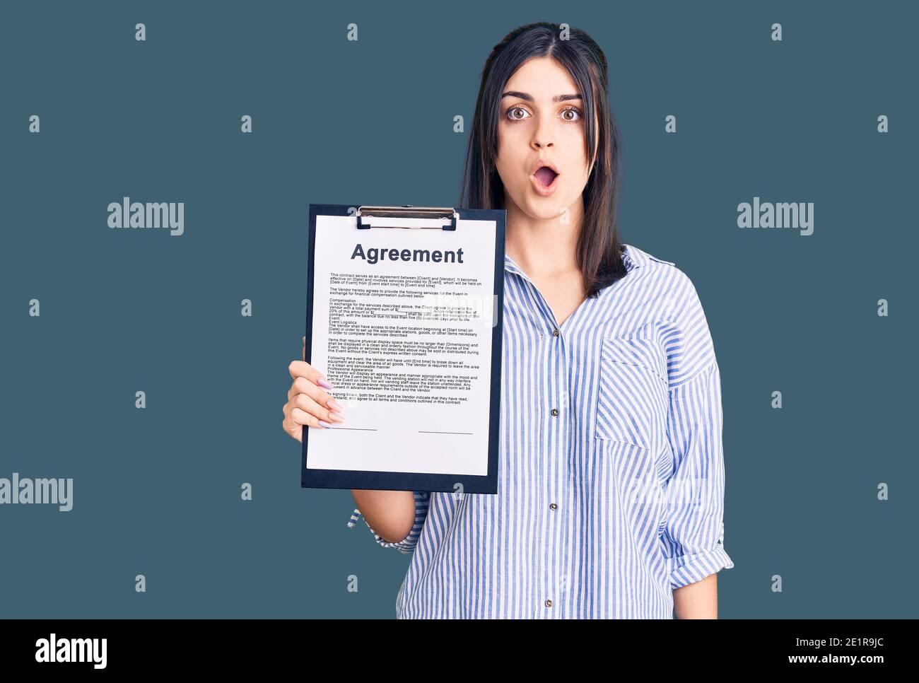 Young beautiful girl holding clipboard with agreement document scared ...