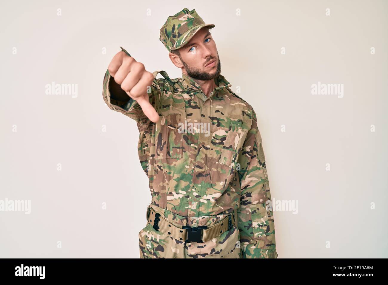 Young caucasian man wearing camouflage army uniform looking unhappy and ...
