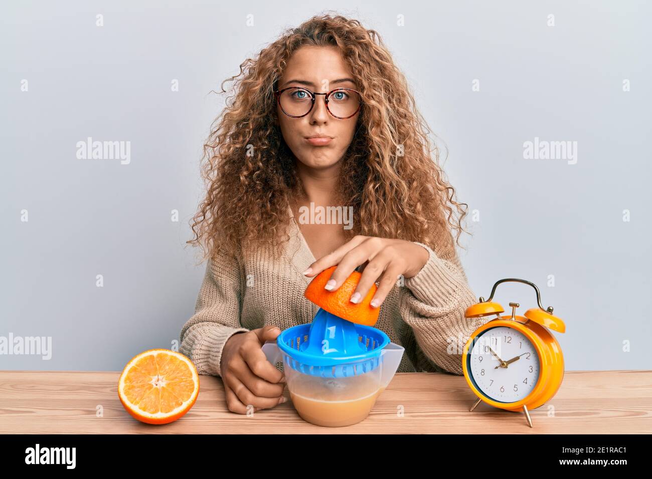 Beautiful caucasian teenager girl making orange juice for breakfast ...