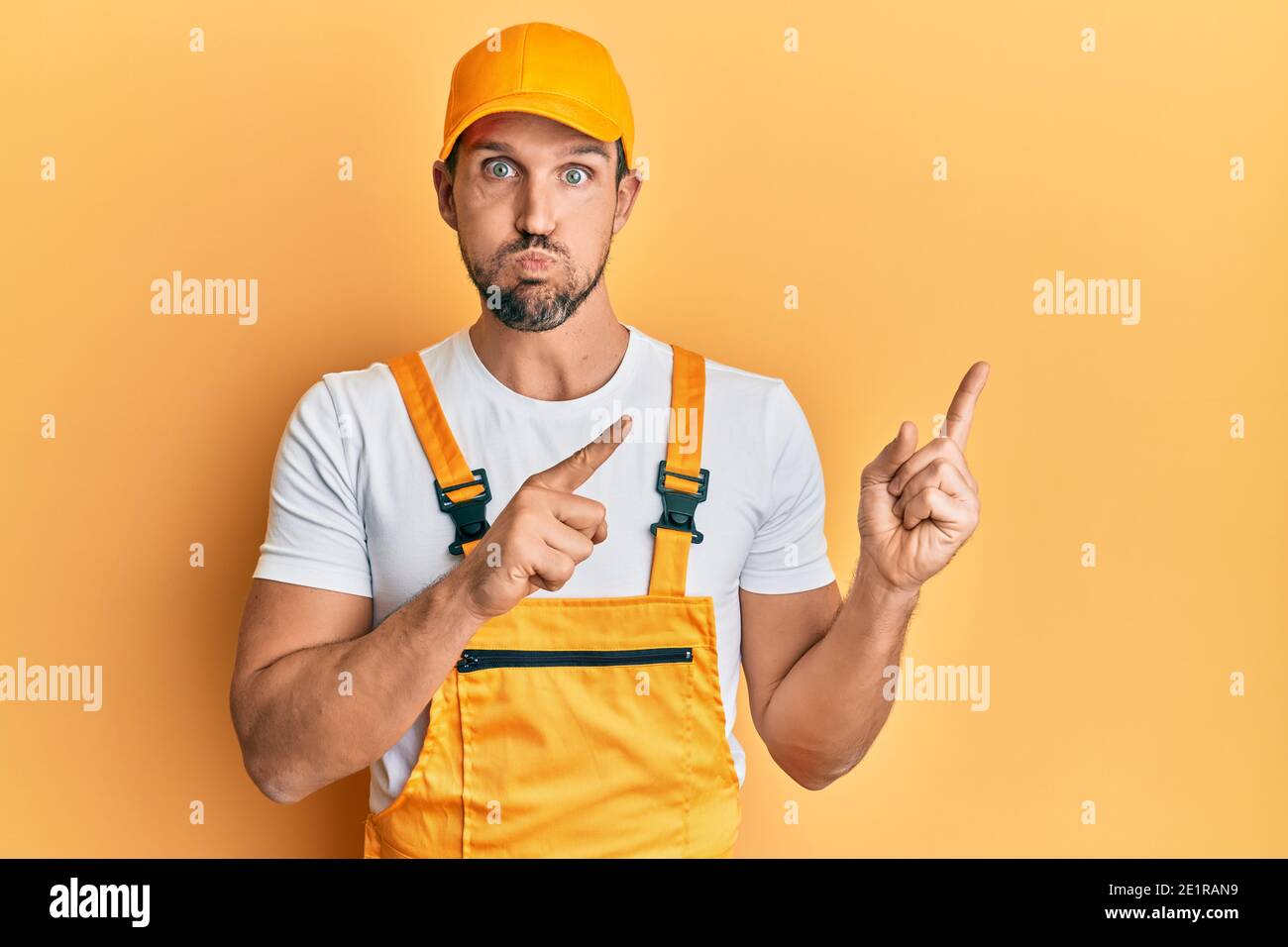 Young handsome man wearing handyman uniform pointing to the side ...