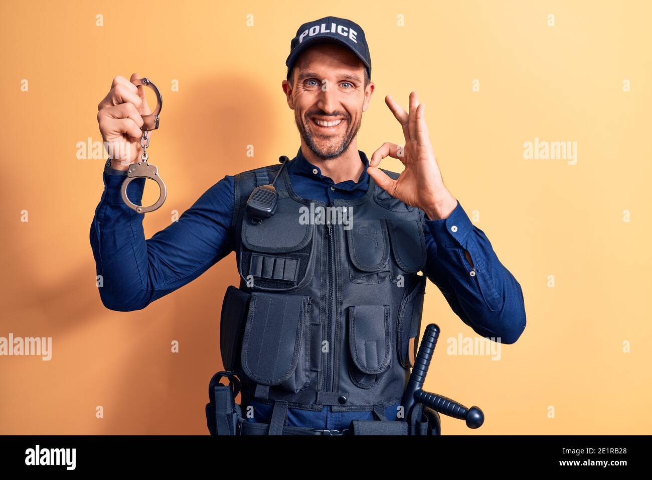 Handsome policeman wearing uniform and bulletprof holding handcuffs ...