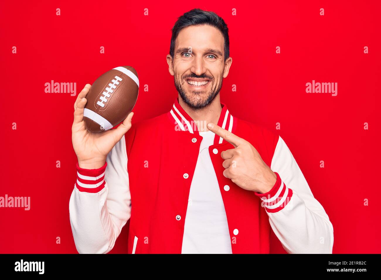 Young handsome player man playing rugby using football ball over ...