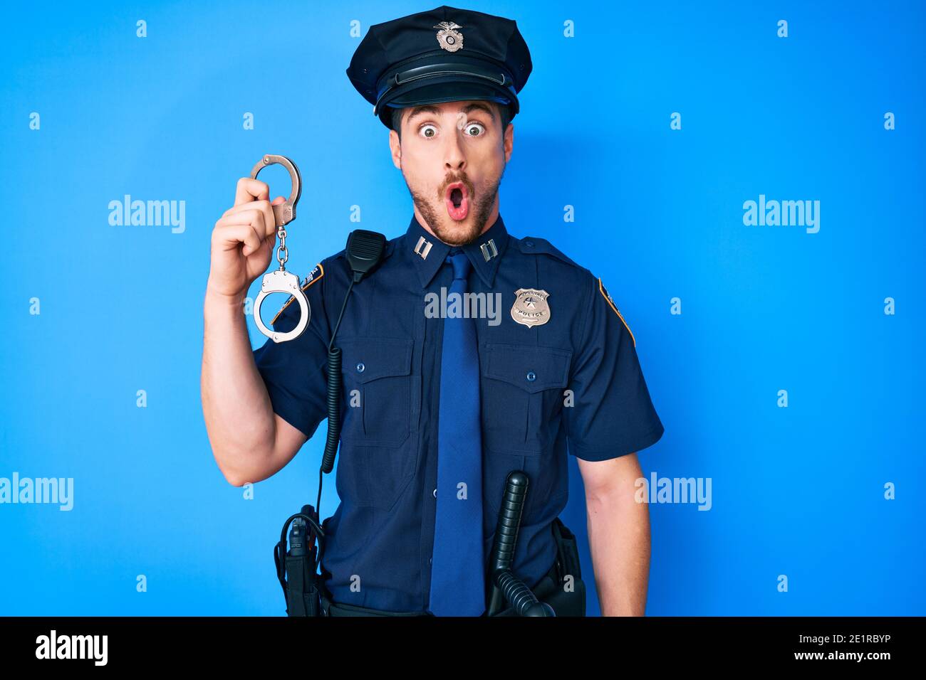 Young Caucasian Man Wearing Police Uniform Holding Handcuffs Scared And