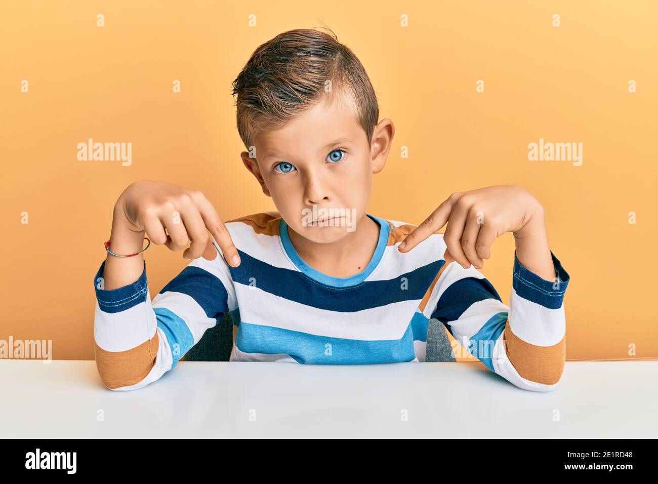 Adorable caucasian kid wearing casual clothes sitting on the table ...