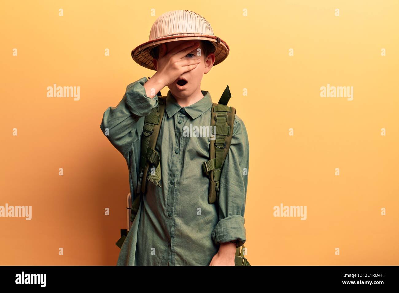 Cute blond kid wearing explorer hat and backpack peeking in shock ...