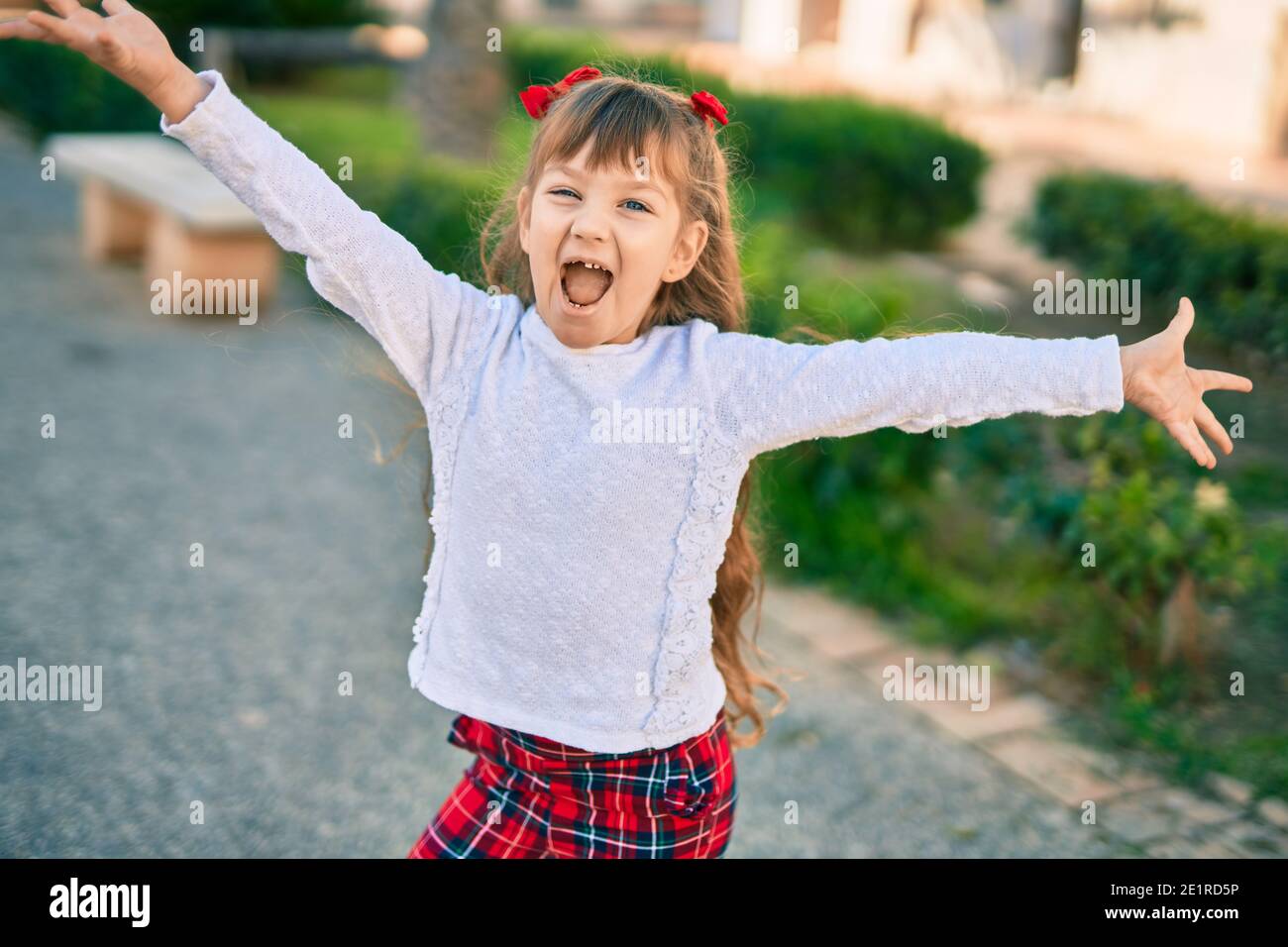 Adorable caucasian child girl with open arms smiling happy at the city ...