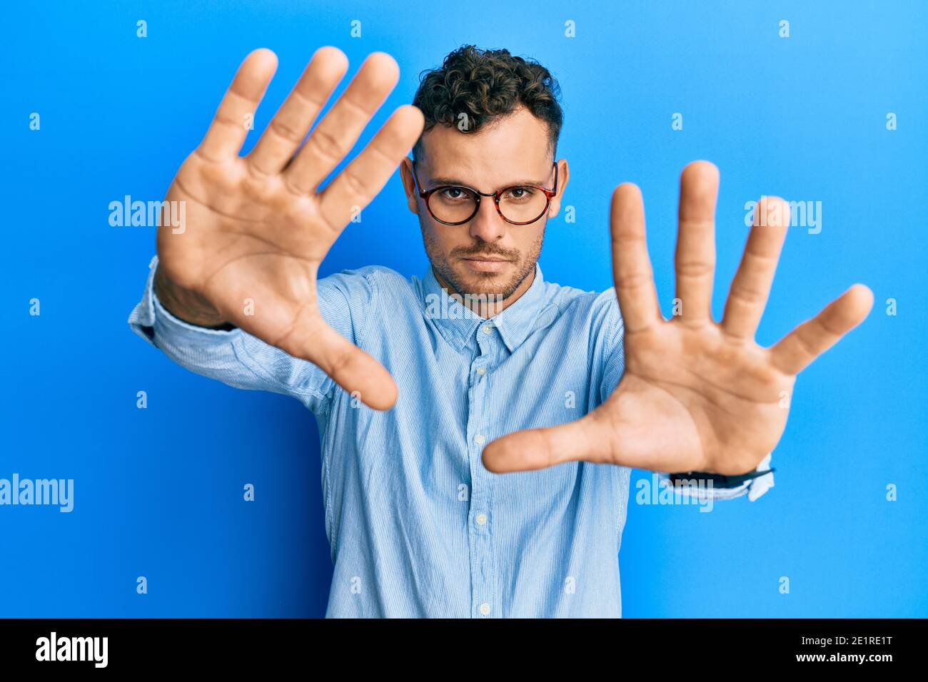 Young hispanic man wearing casual clothes and glasses doing frame using ...