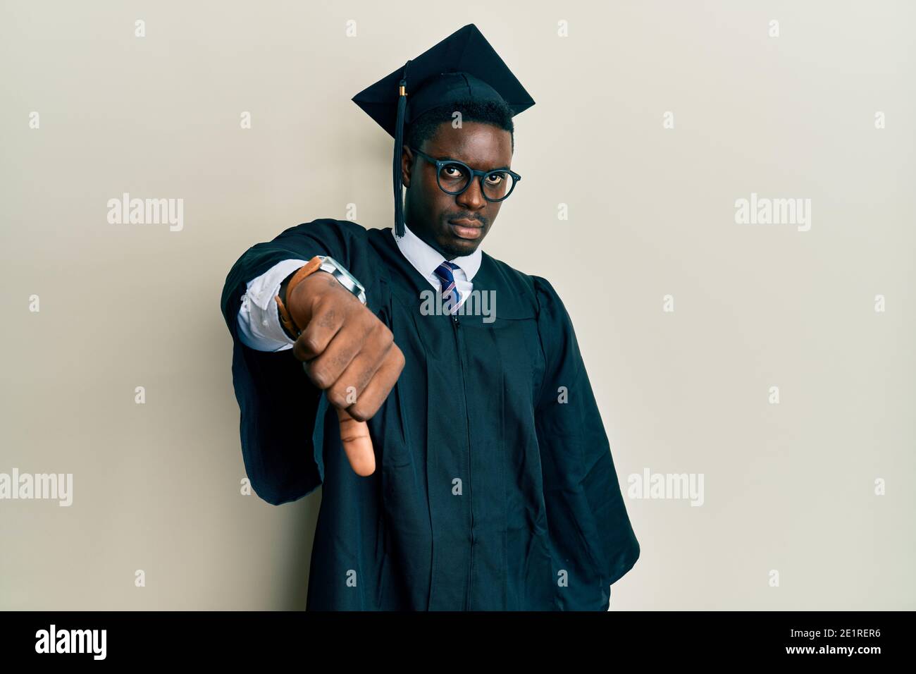 Handsome black man wearing graduation cap and ceremony robe looking ...