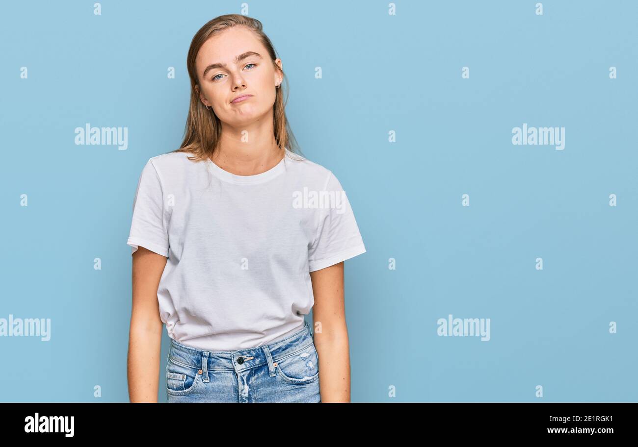 Beautiful young blonde woman wearing casual white t shirt looking ...