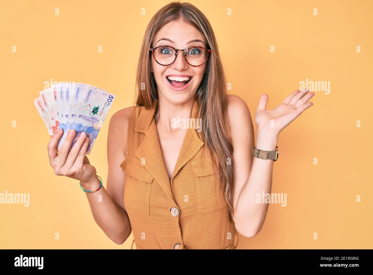 Young blonde girl holding colombian pesos celebrating victory with ...