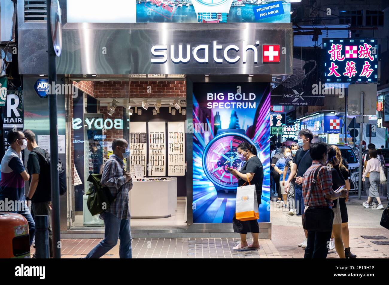 Pedestrians wearing face masks walk past the Swiss multinational ...