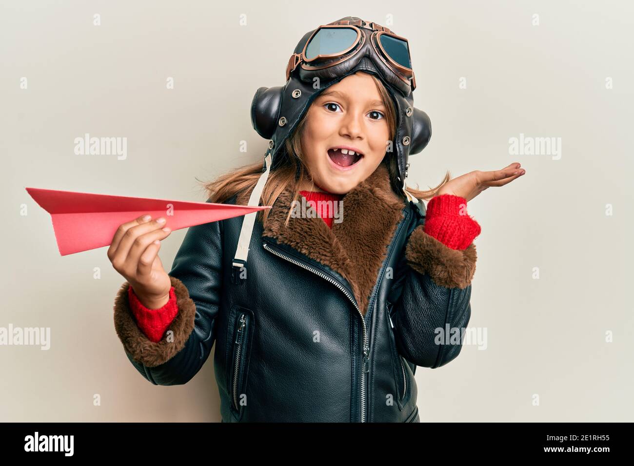 Little beautiful girl wearing pilot uniform holding paper plane ...