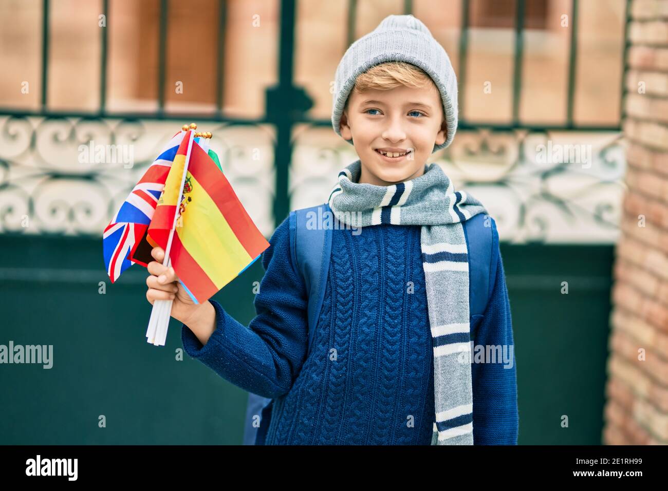 Adorable blond student kid smiling happy holding flags of different ...