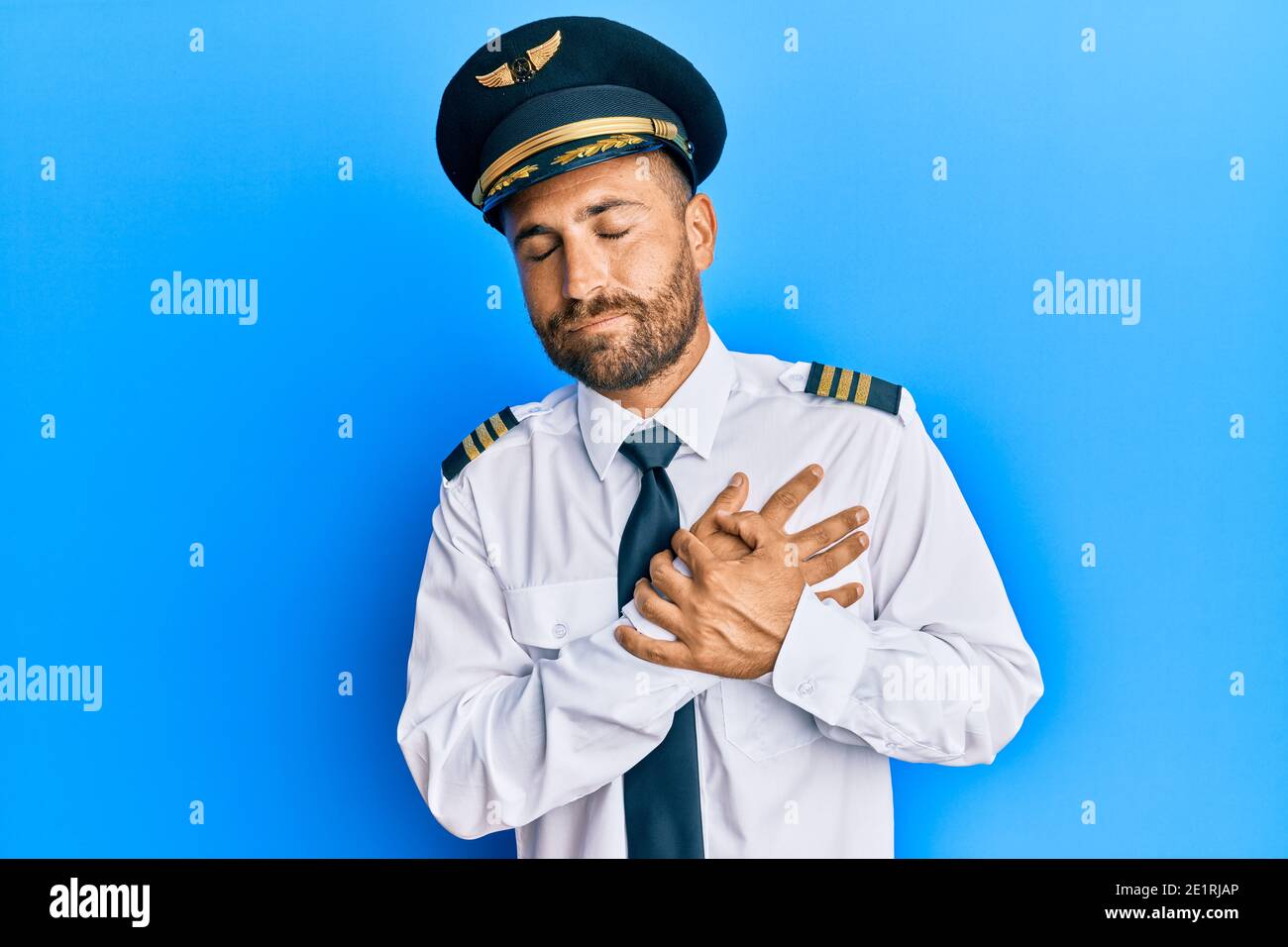 Handsome man with beard wearing airplane pilot uniform smiling with ...
