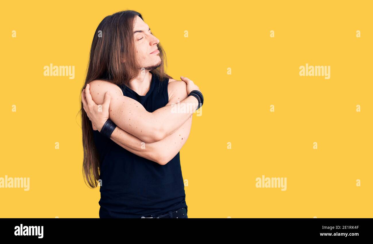 Young adult man with long hair wearing goth style with black clothes ...
