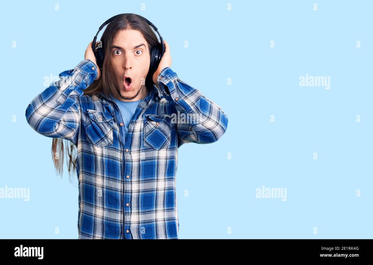 Young adult man with long hair listening to music using headphones ...